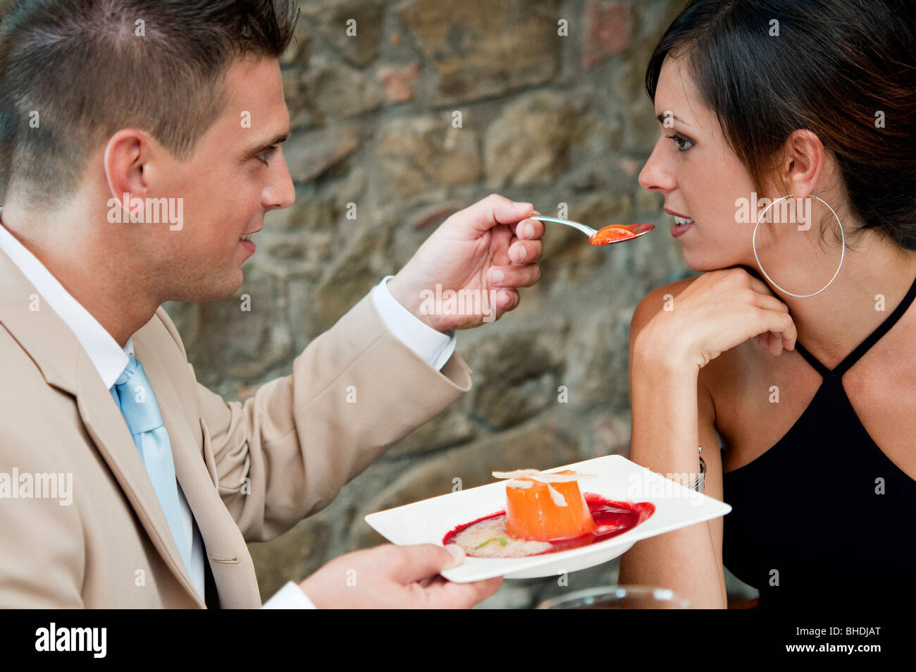 Young man feeding young woman at restaurant Stock Photo - Alamy
