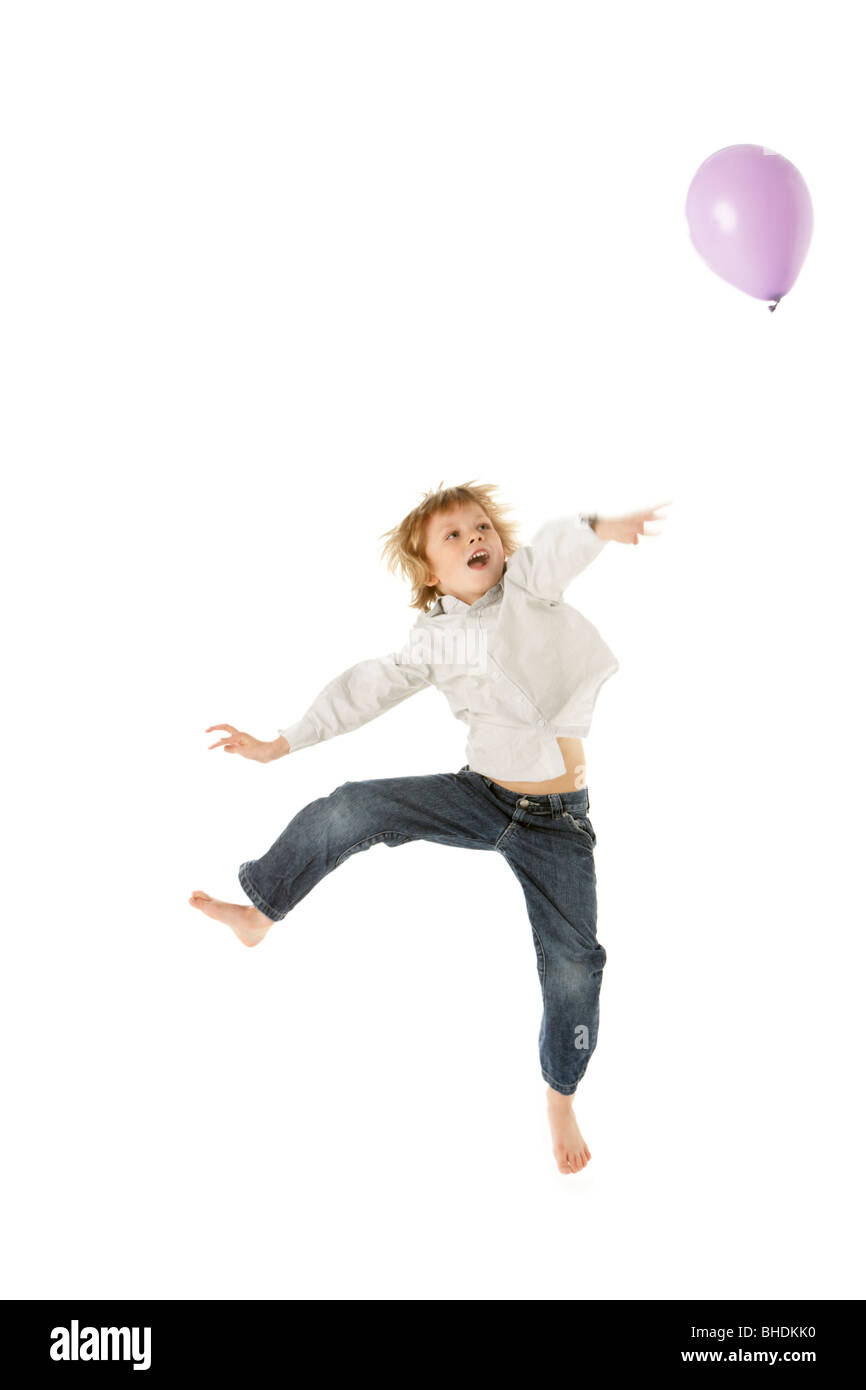Young Boy Jumping With Balloon In Studio Stock Photo - Alamy