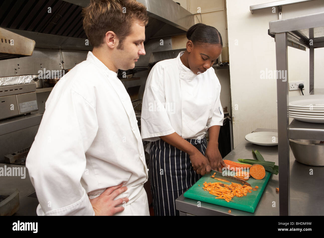 Chef Instructing Trainee In Restaurant Kitchen Stock Photo - Alamy
