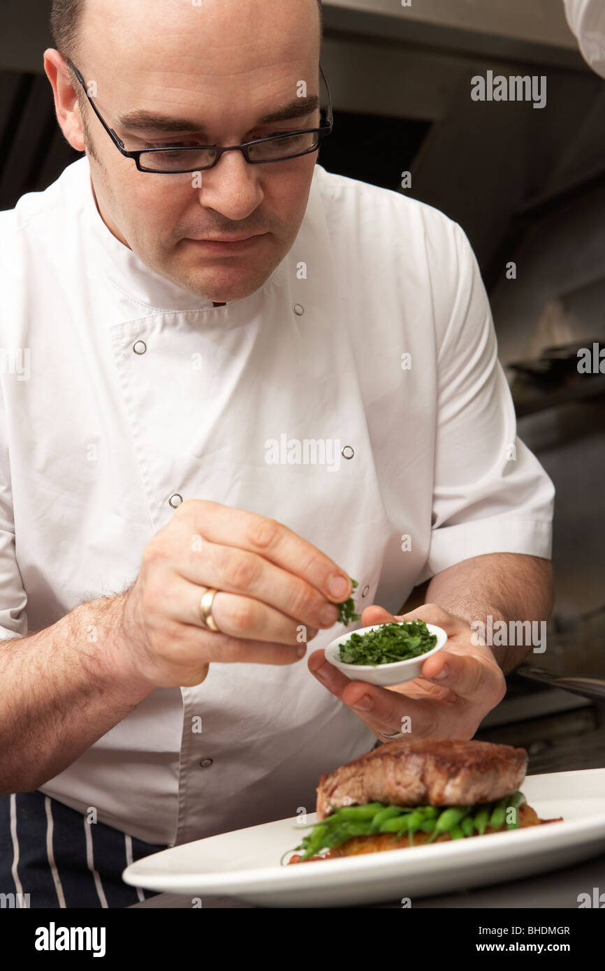 Chef Adding Seasoning To Dish In Restaurant Kitchen Stock Photo - Alamy