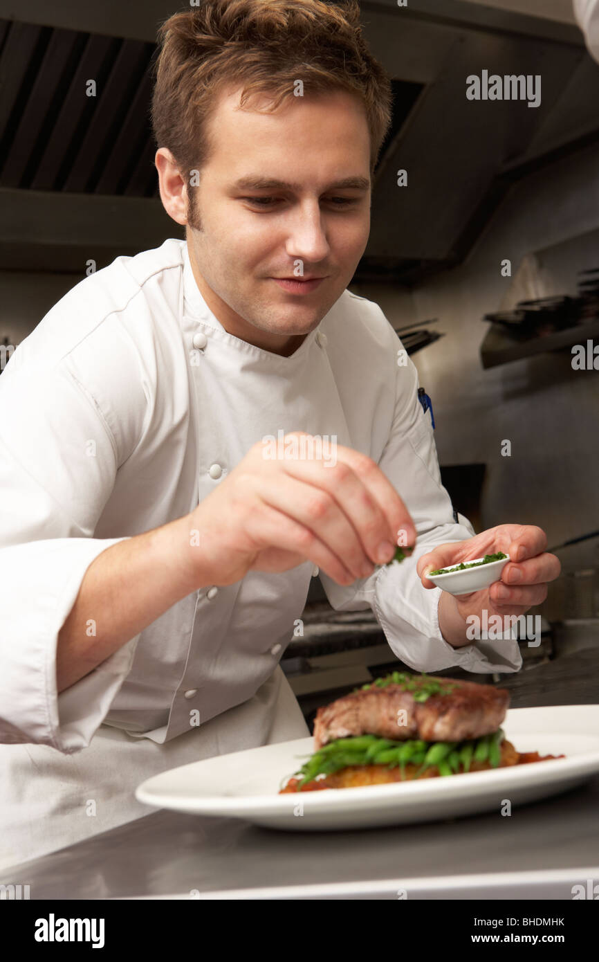 Chef Adding Seasoning To Dish In Restaurant Kitchen Stock Photo - Alamy