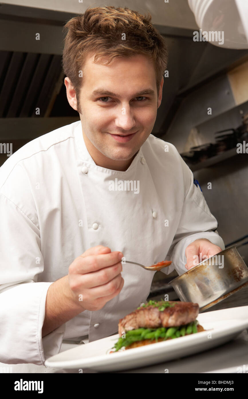 Chef Adding Sauce To Dish In Restaurant Kitchen Stock Photo - Alamy