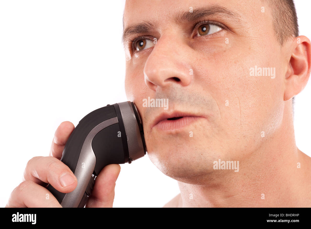 Close up portrait of a handsome young man using an electric shaver ...