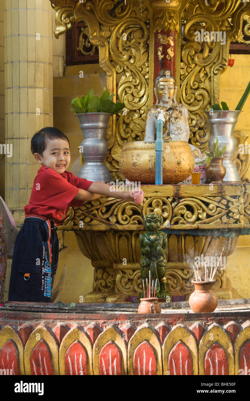 Young Burmese boy pouring water on the Buddha, Sule Pagoda Rangoon ...