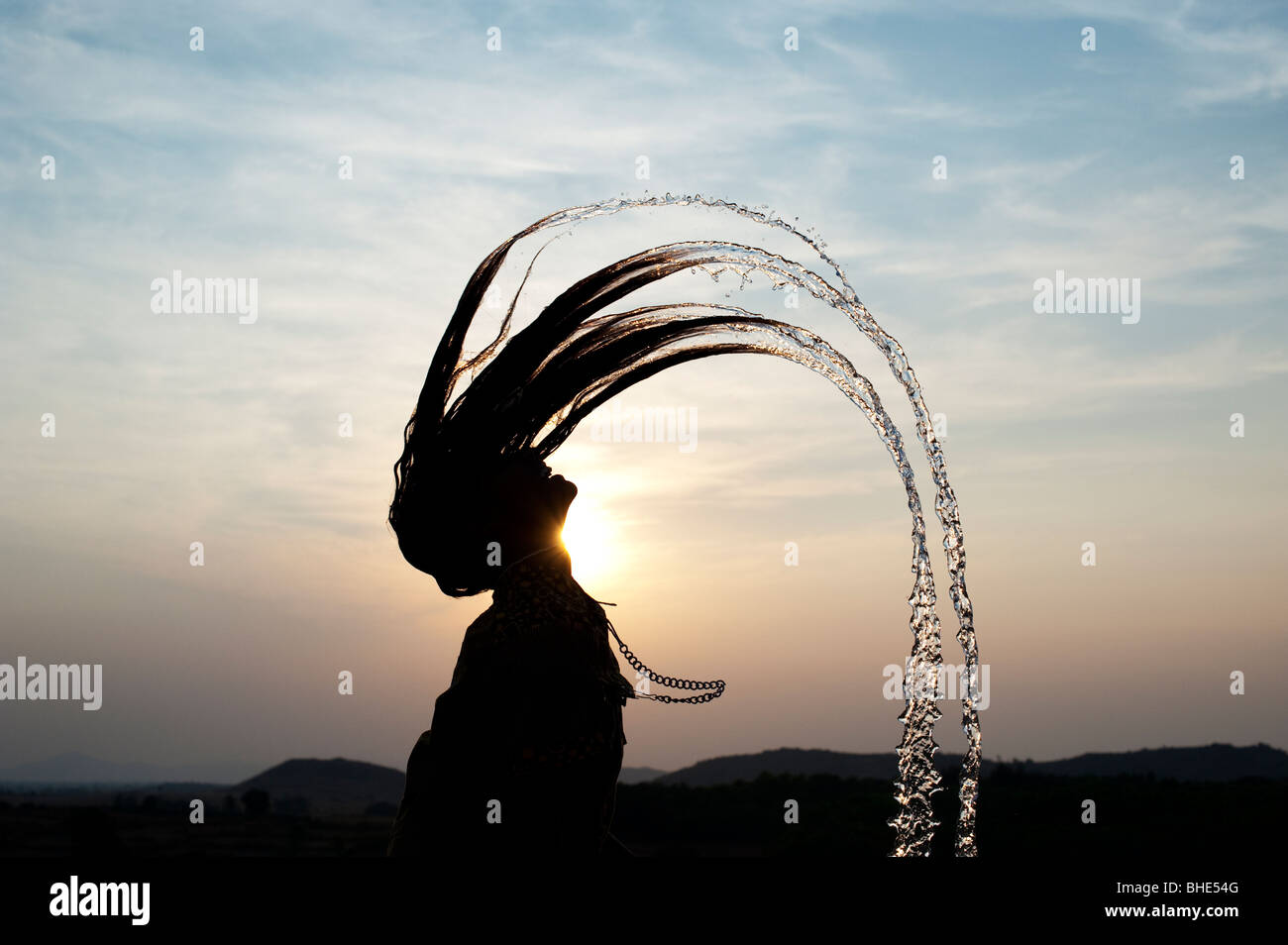 Indian girl throwing her wet hair back causing water spray silhouette ...