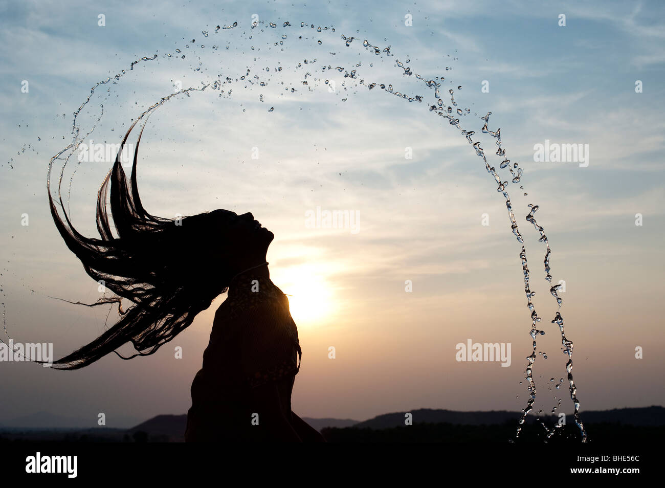Indian girl throwing her wet hair back causing water spray silhouette ...