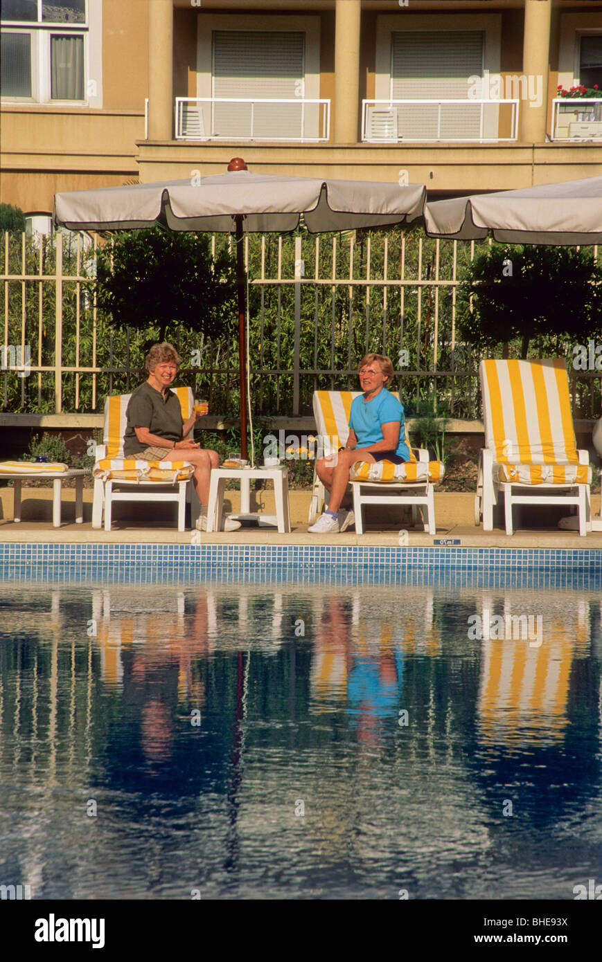 Two women sitting by pool Stock Photo - Alamy