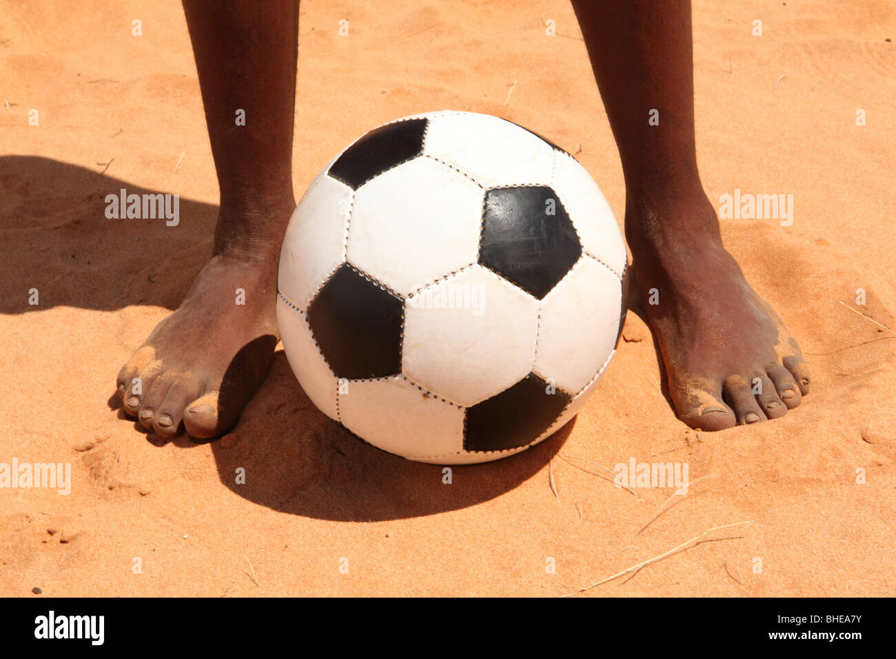 A person stands with a soccer ball at their feet on a football field in ...