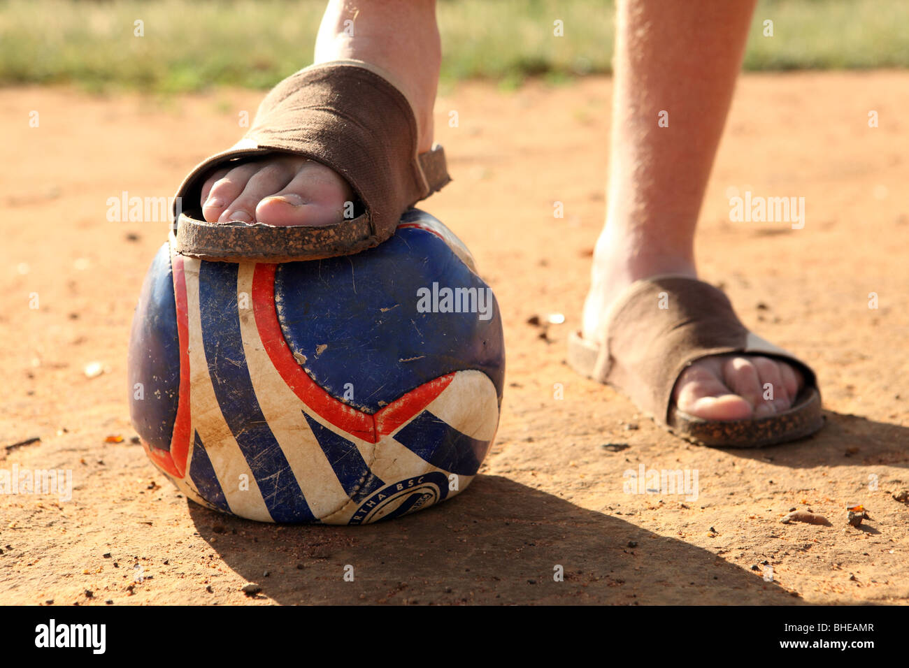 A person stands with a soccer ball at their feet on a football field in ...