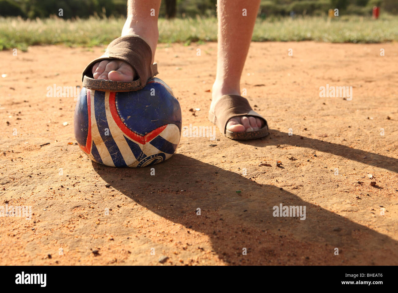 A person stands with a soccer ball at their feet on a football field in ...