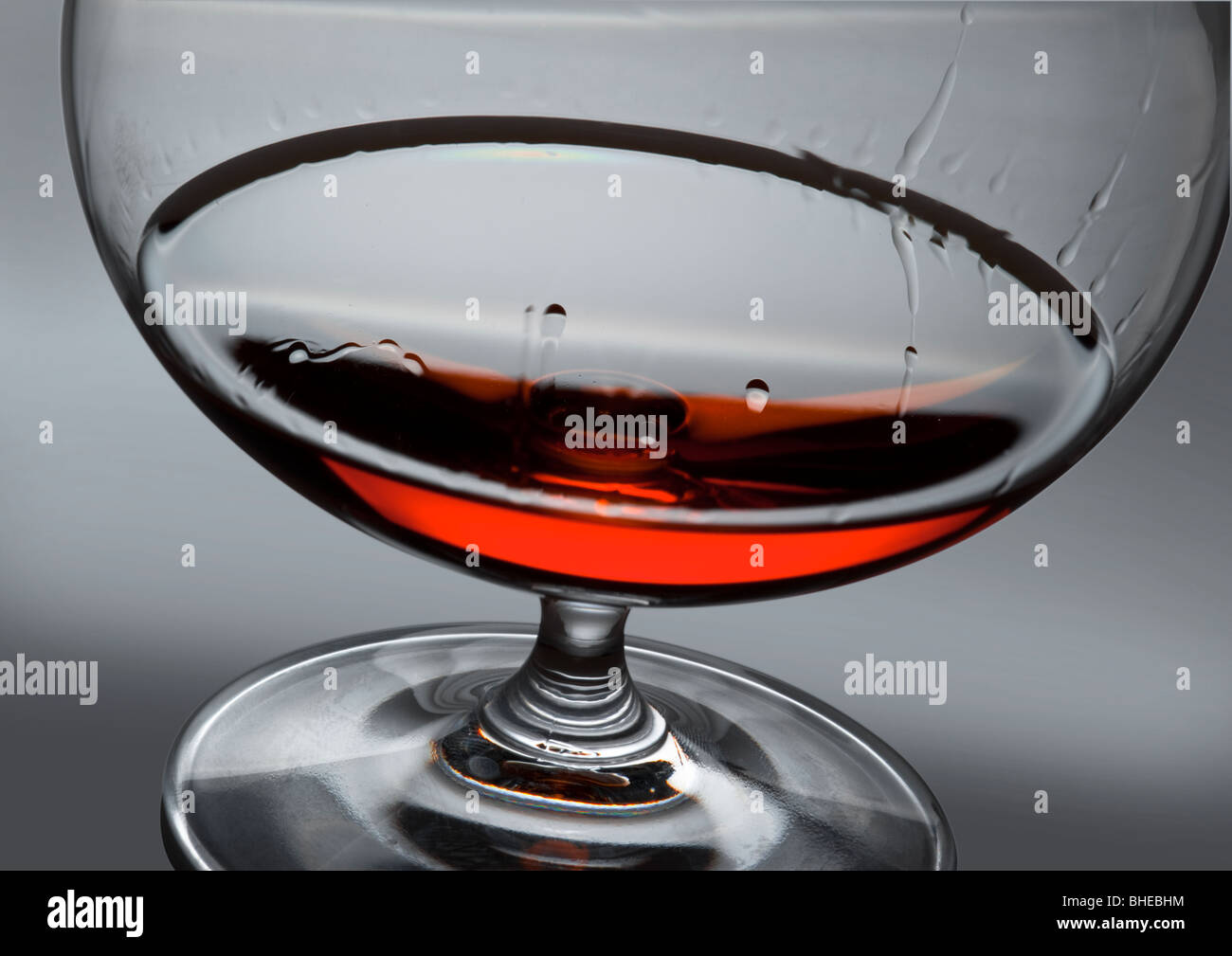 Detailed shooting of a glass with alcohol on a gleam, liquid drops flow ...