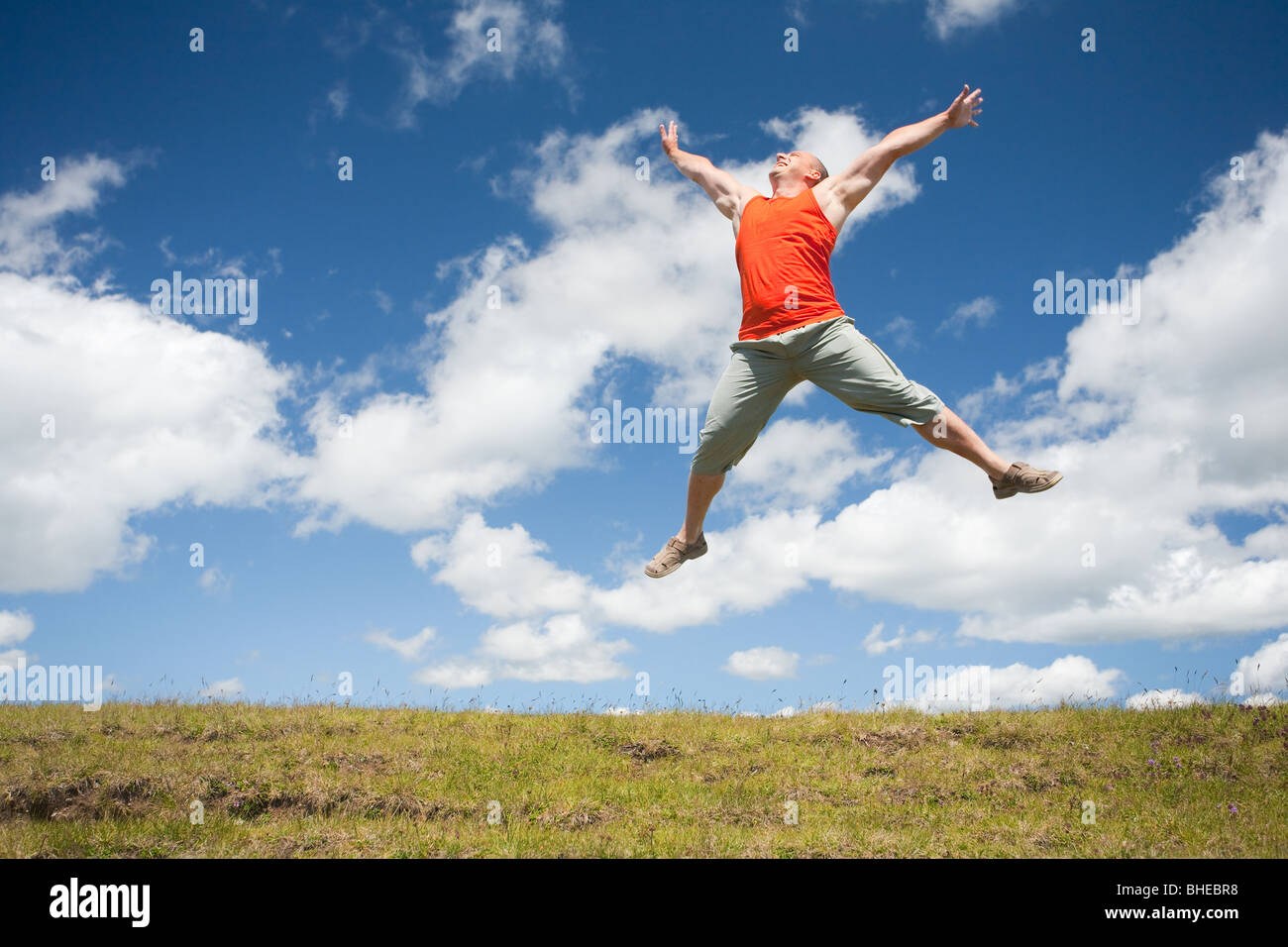 Young man jumping for joy in a beautiful landscape with blue sky and ...