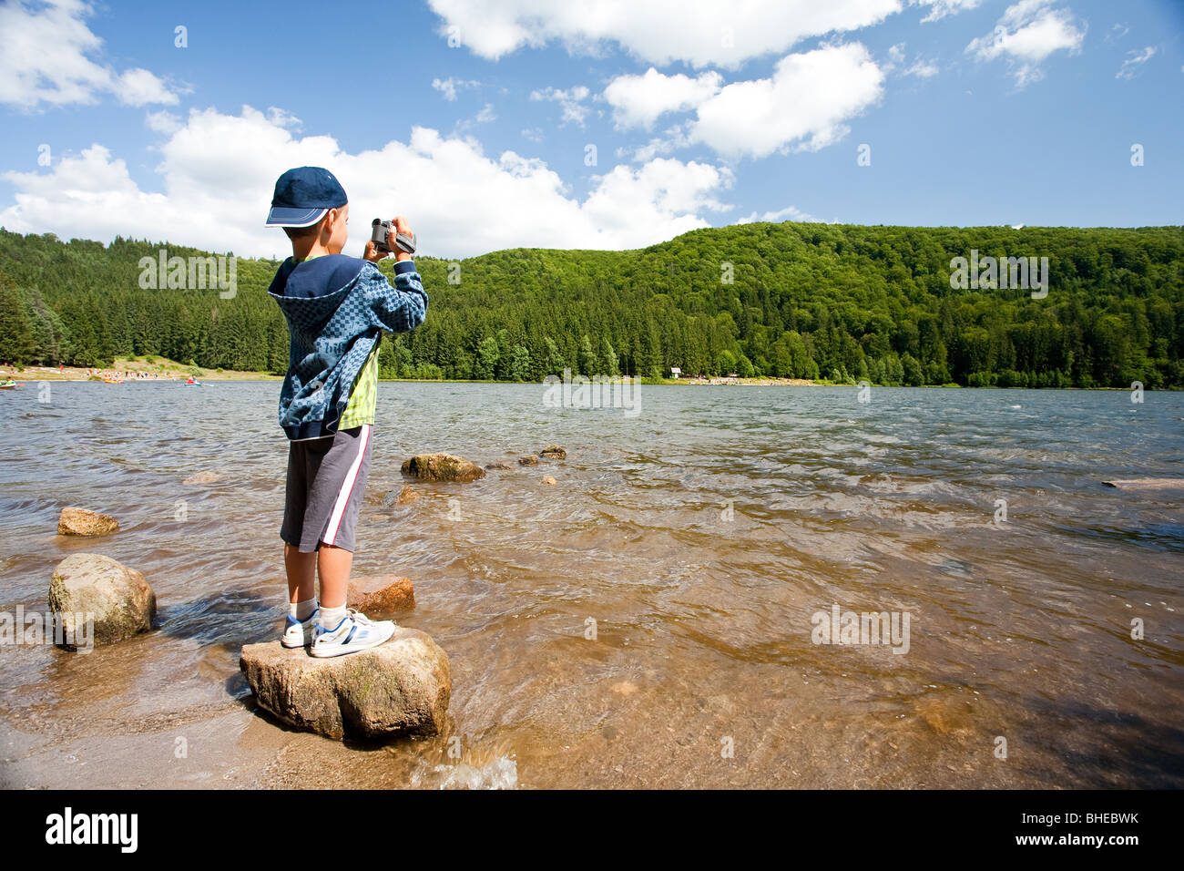 Boy filming the beautiful landscape with a lake and pine forest Stock ...