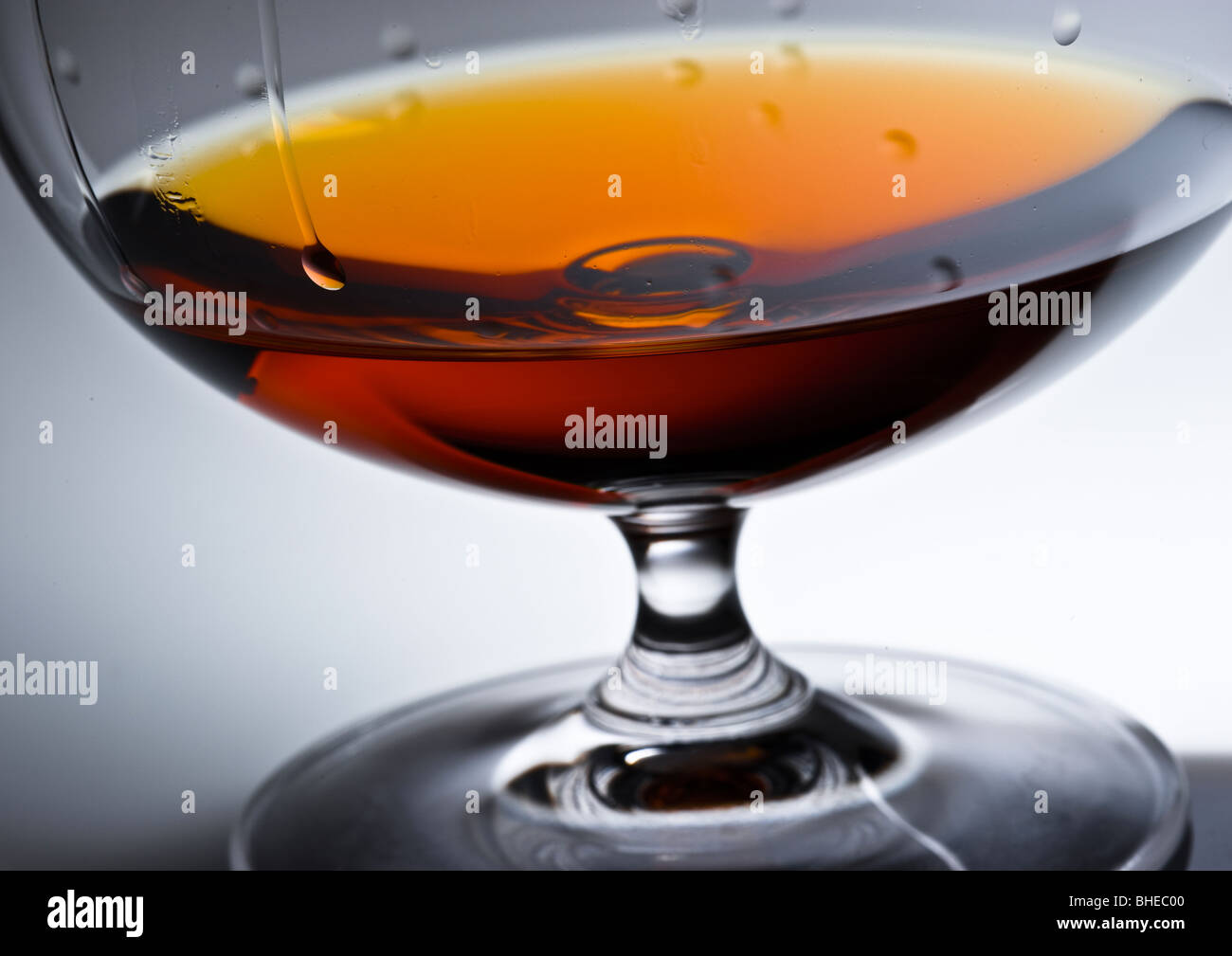 Detailed shooting of a glass with alcohol on a gleam, liquid drops flow ...