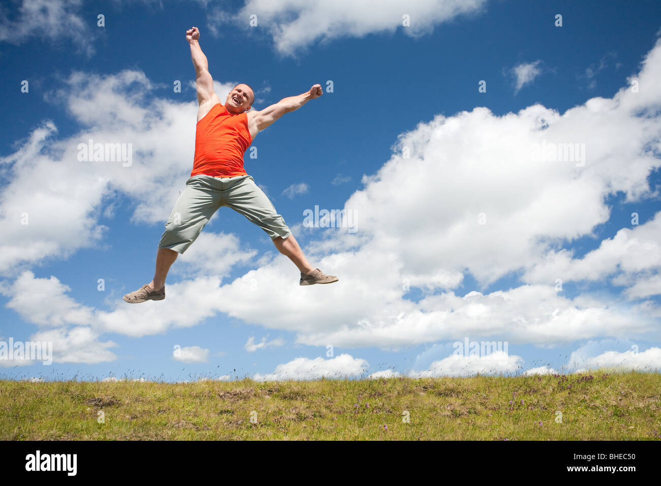 Young man jumping for joy in a beautiful landscape with blue sky and ...