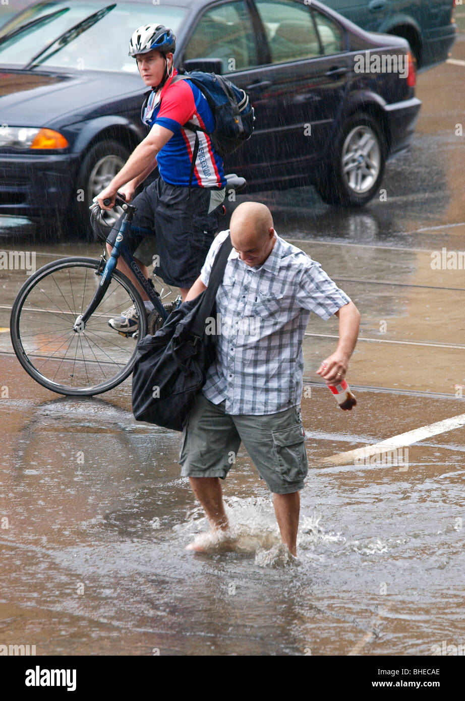 OLDER MAN WALKING THROUGH LARGE PUDDLE AFTER HEAVY RAIN SWANSTON STREET ...