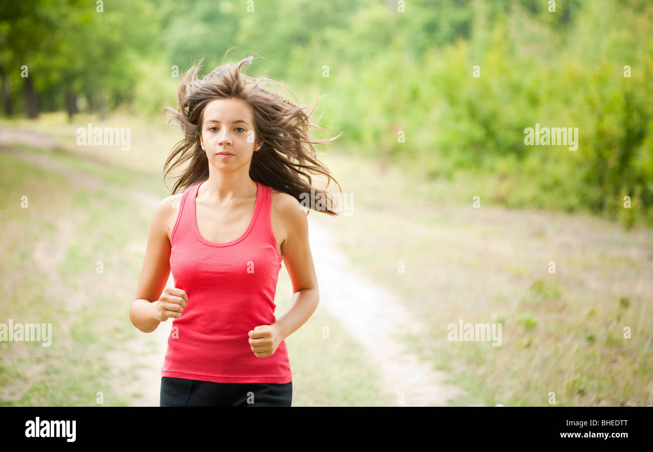 Young woman running outdoor through a forest Stock Photo - Alamy