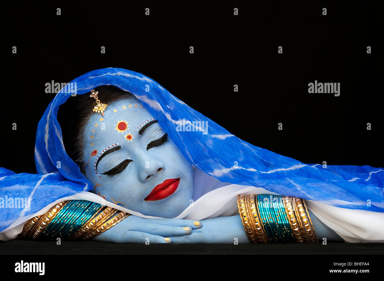 Indian girl, face painted as the Hindu goddess Sita against a black ...