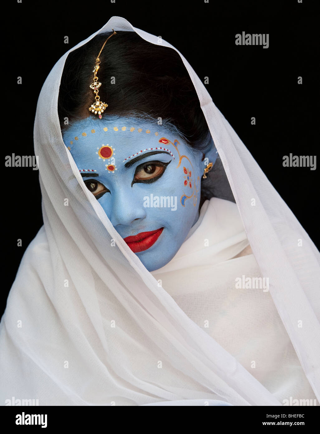 Indian girl, face painted as the Hindu goddess Sita against a black ...