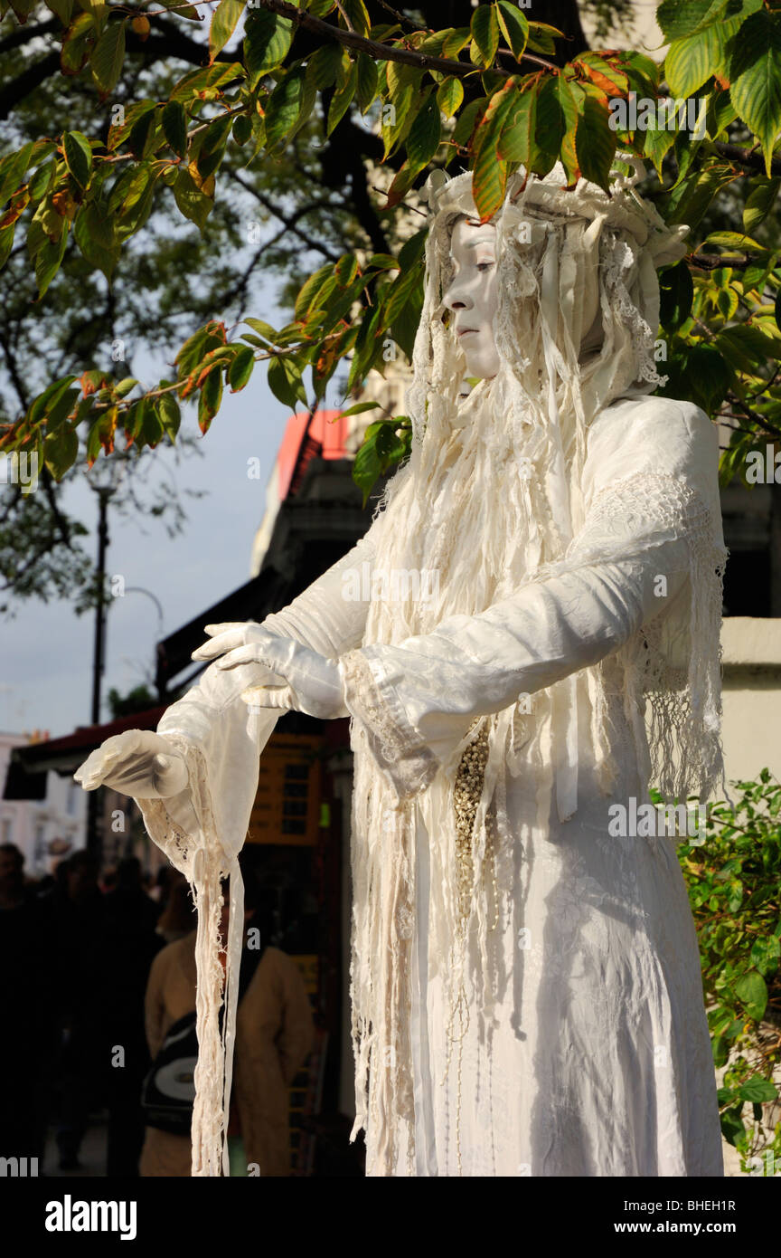A female 'living statue', dressed extravagantly in white with lacy ...