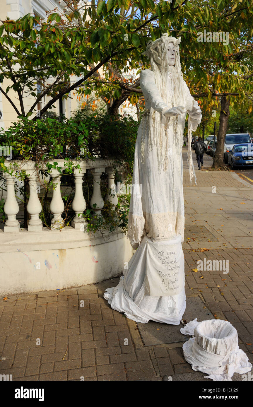 A female 'living statue', dressed extravagantly in white with lacy ...