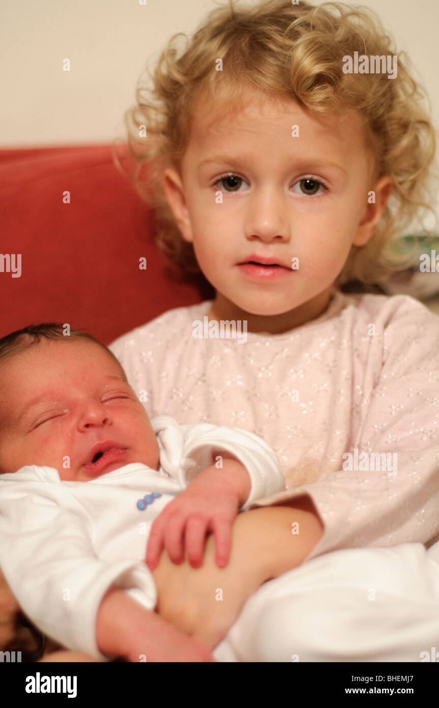 young Child holds newborn baby Model release available Stock Photo - Alamy