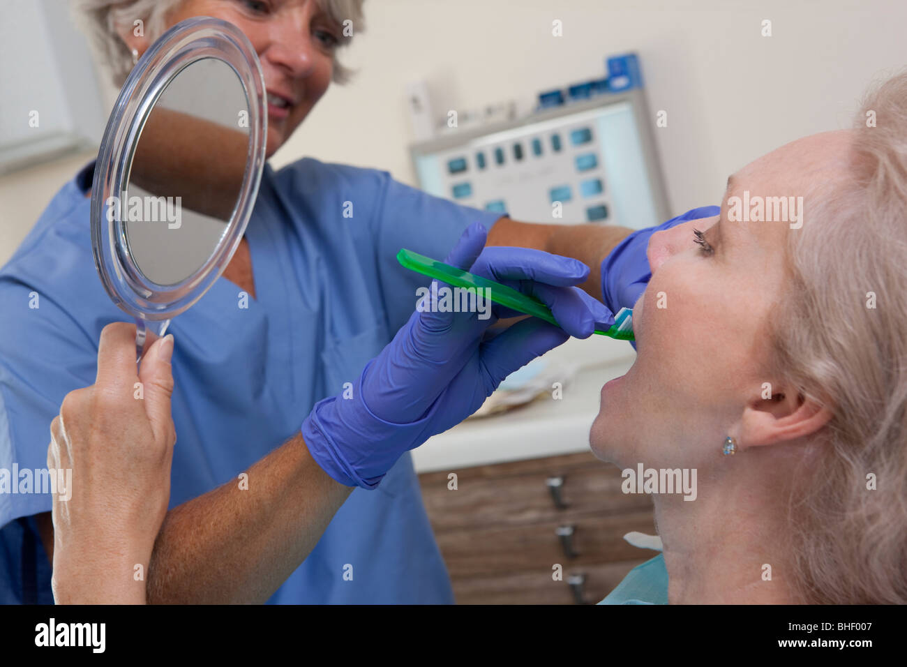 Female dentist brushing the teeth of a patient Stock Photo - Alamy