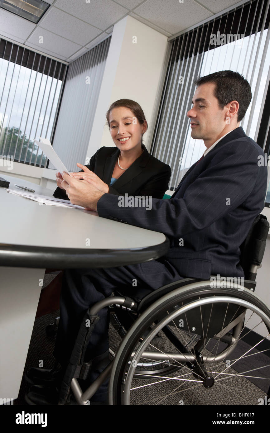 Handicapped businessman and a businesswoman working in an office Stock ...