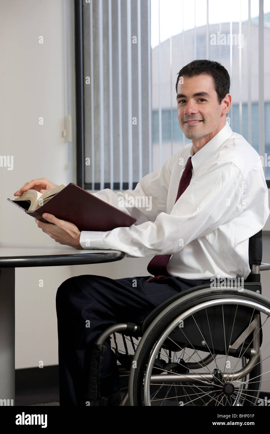 Handicapped businessman holding a book and smiling Stock Photo - Alamy