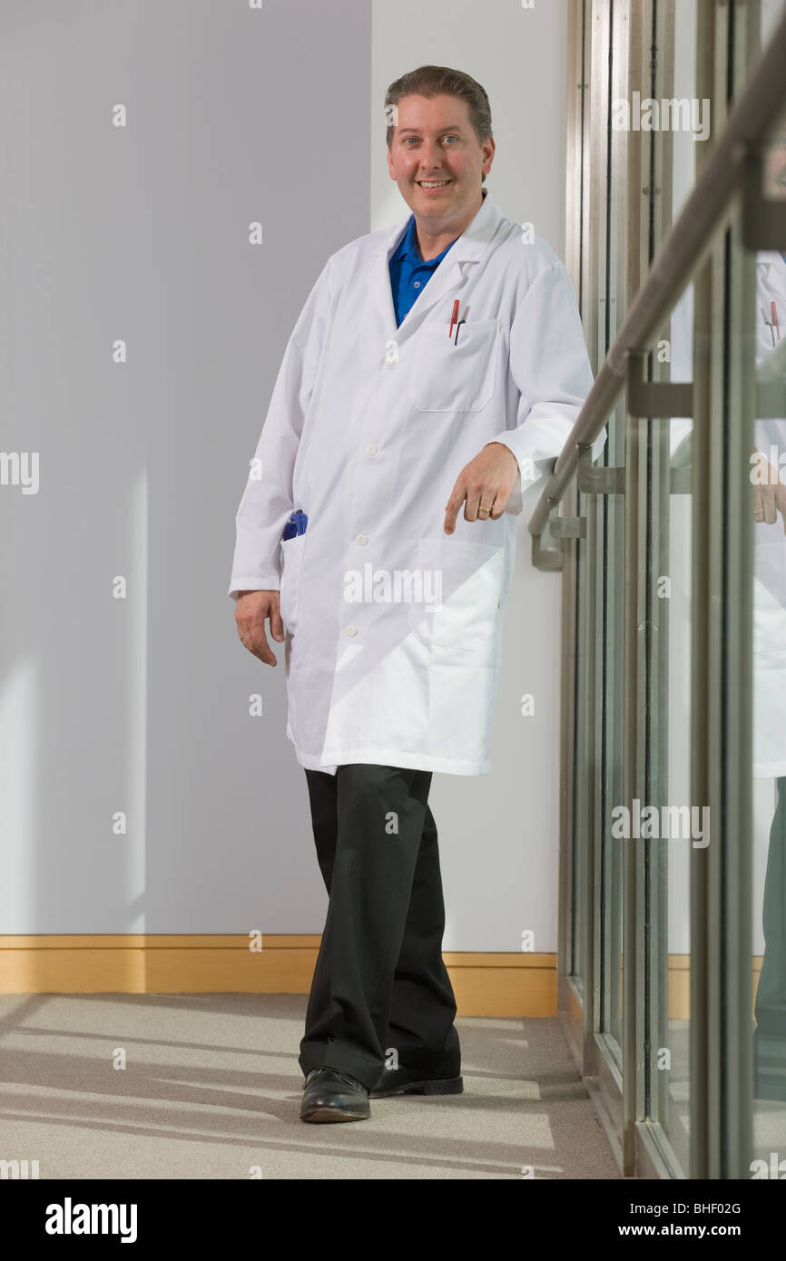 Doctor leaning against a railing of a hospital Stock Photo - Alamy