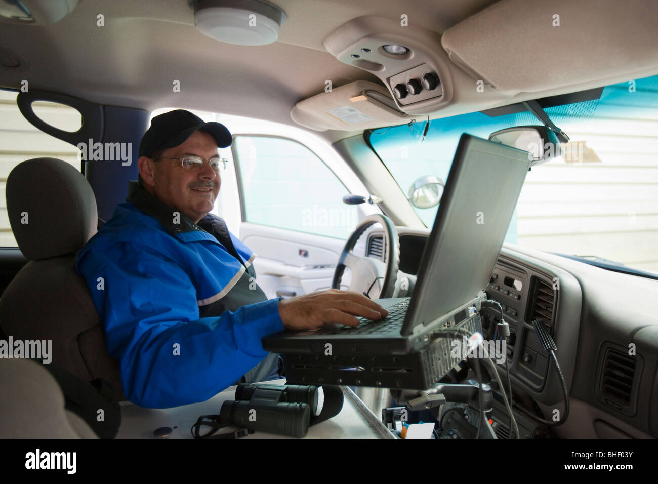 Security guard using a laptop in a vehicle Stock Photo - Alamy