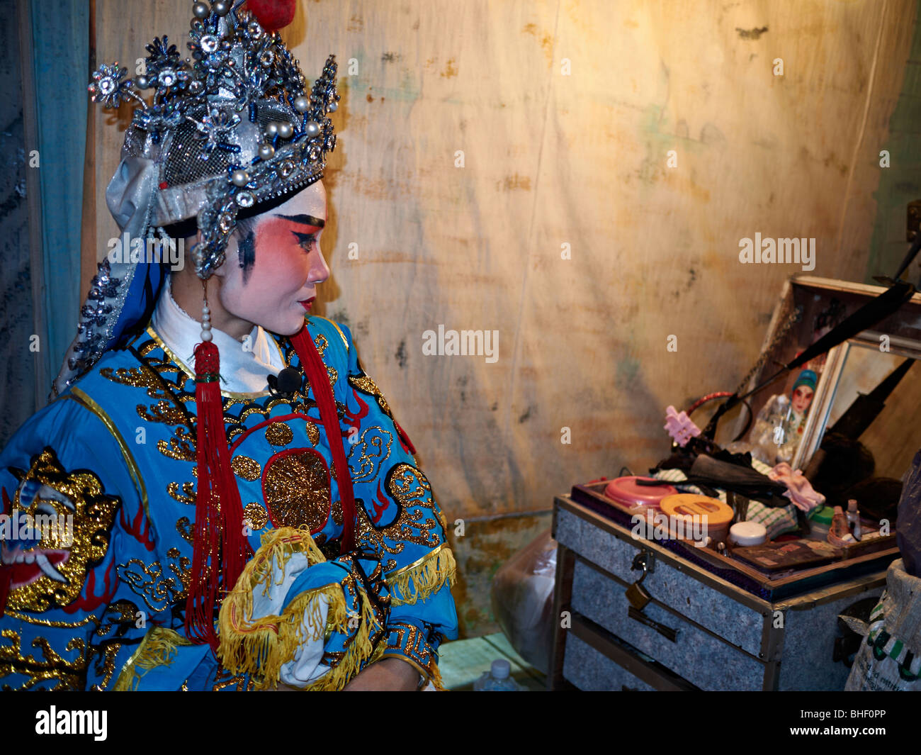 Chinese opera actor, backstage, in traditional colourful costume and ...