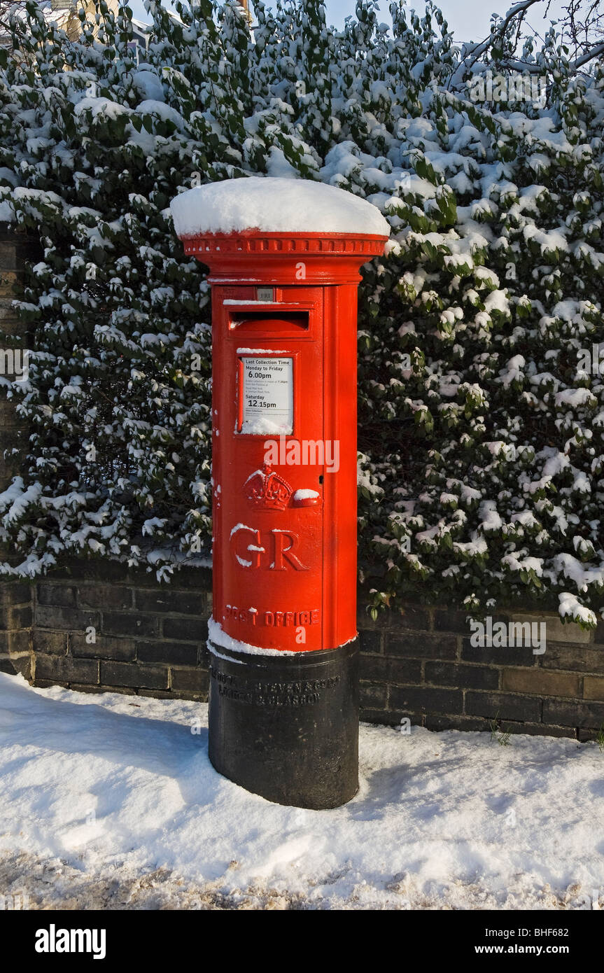 Traditional British red postbox post box covered in snow in winter York ...