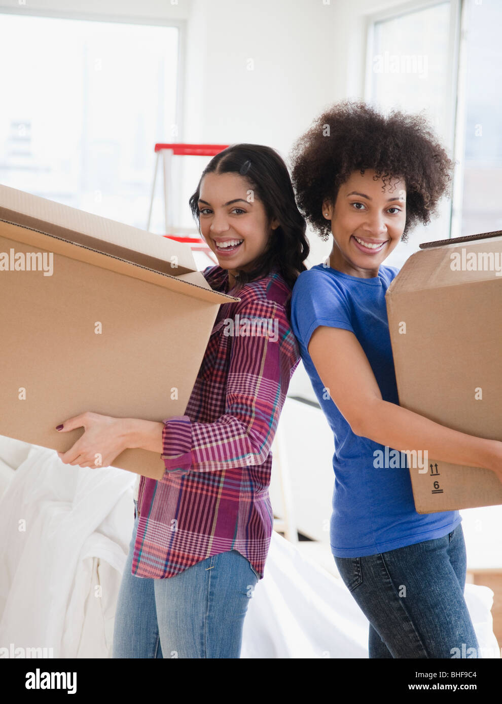 Friends carrying cardboard moving boxes Stock Photo - Alamy