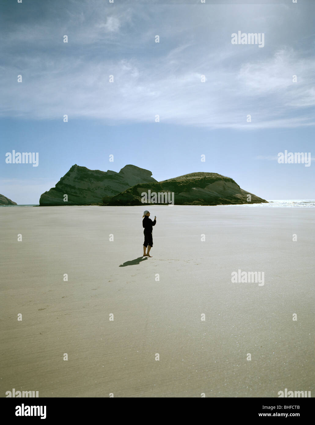 Woman on sweeping sandy beach at lowtide, Wharariki Beach, North coast ...