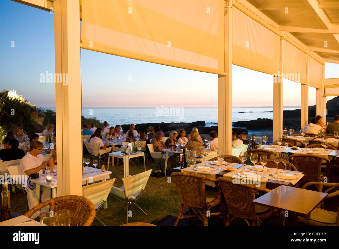 Tourists dining in a fish Restaurant on the beach at sunset, Praia do ...
