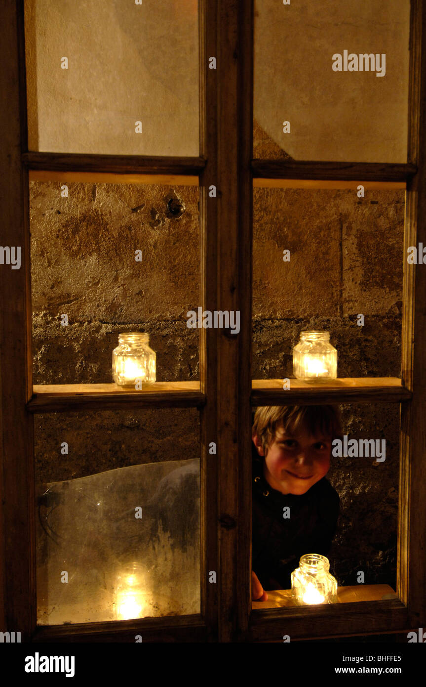 A boy looking through a candle-lit window at the christmas market ...