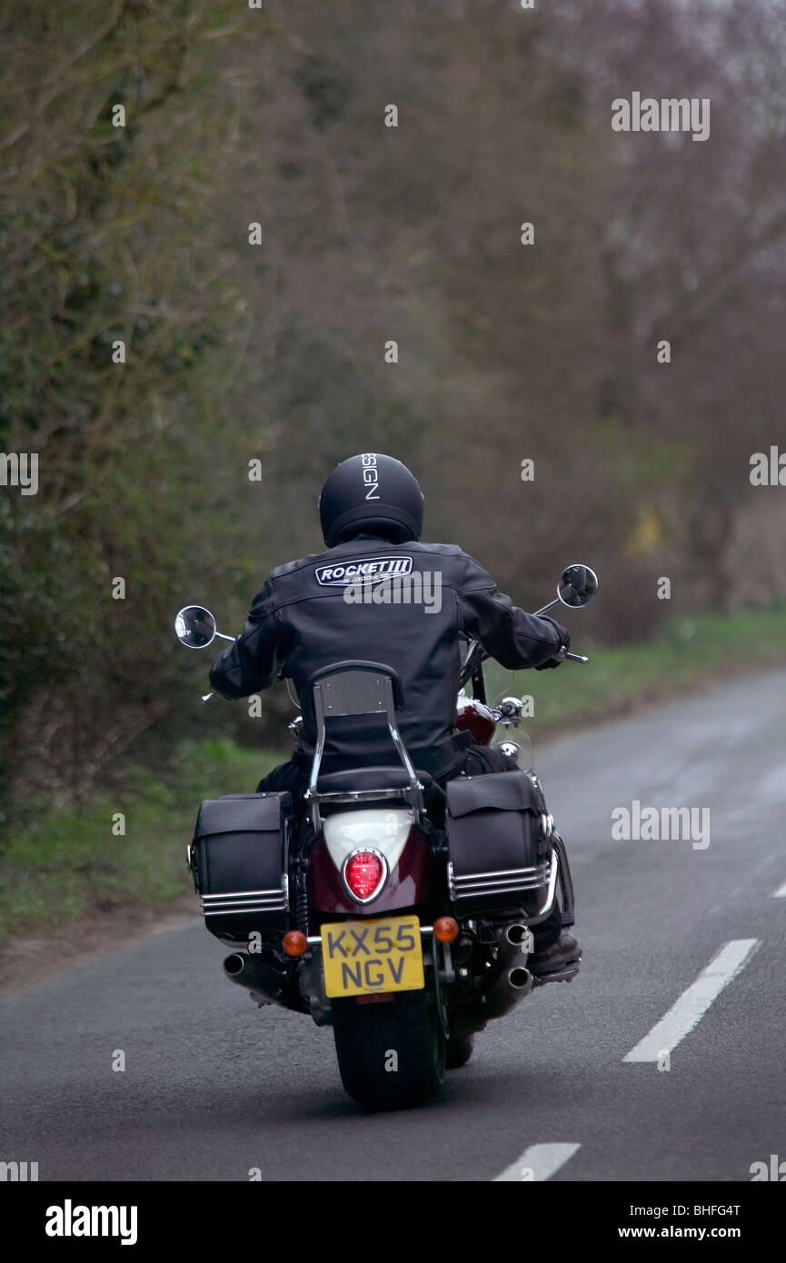 Rider traveling along country road on a Triumph Rocket III motorcycle ...