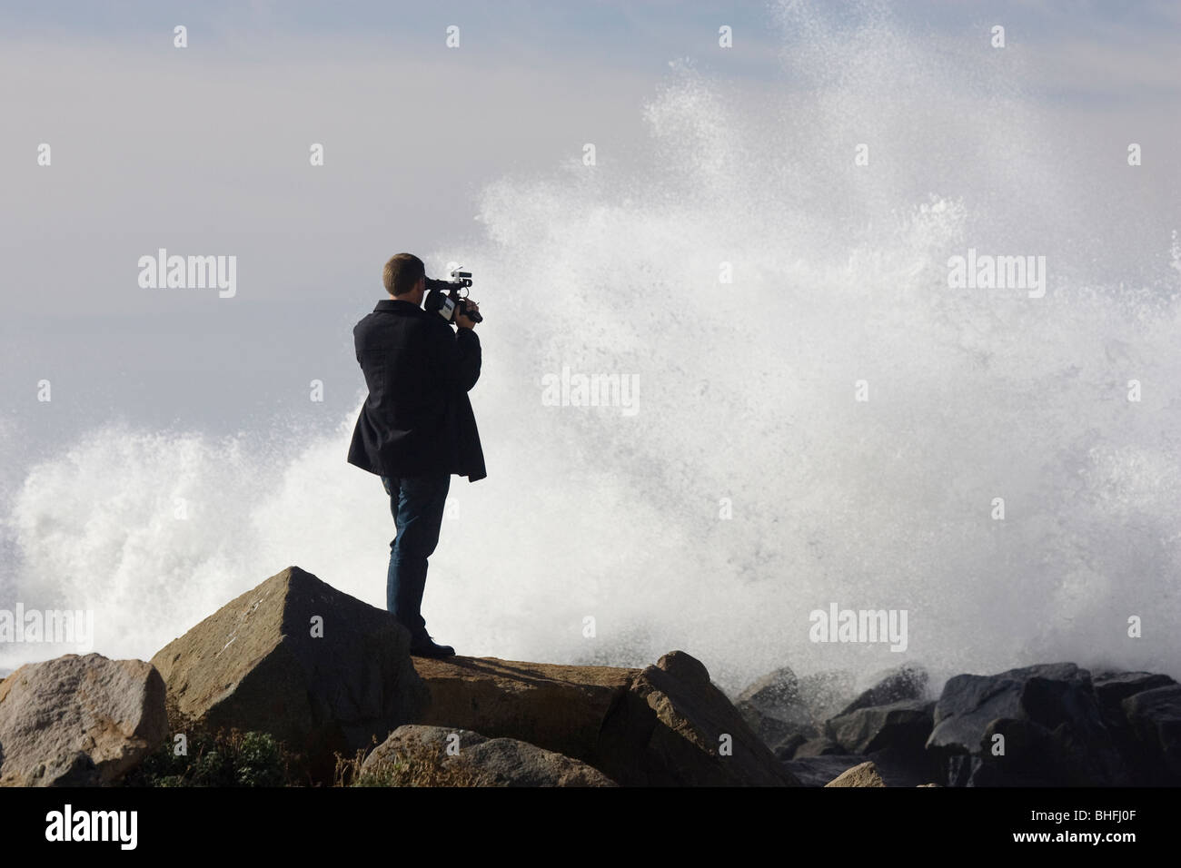 Man with Video Camera Standing on Rock Jetty Shooting Crashing Waves ...