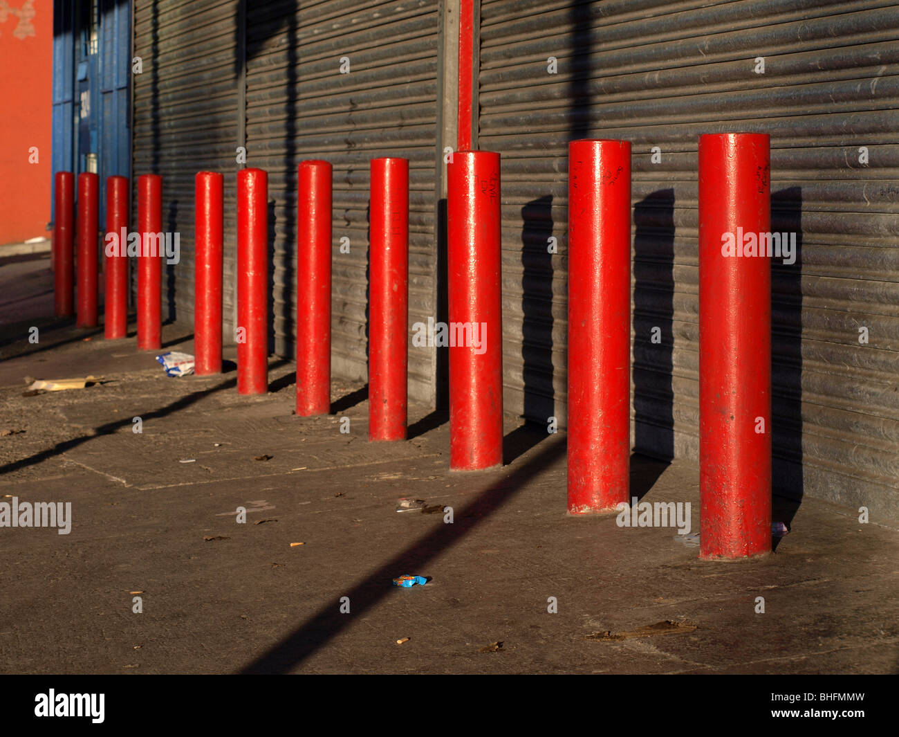 a line of bright red sunlit posts cast shadows on shutters Stock Photo ...