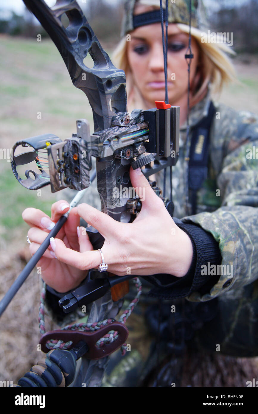 YOUNG WOMAN 21 Y.O. FEMALE HUNTER SITTING ON LOG PREPARING 80 POUND BOW ...
