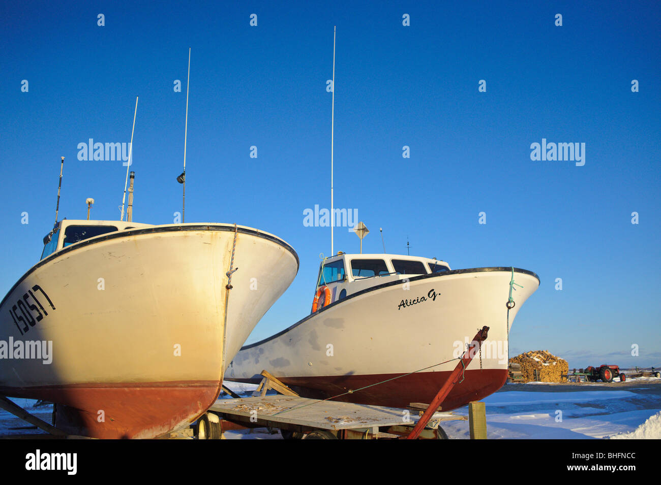Lobster boats out of the water during winter along the frozen shores of ...