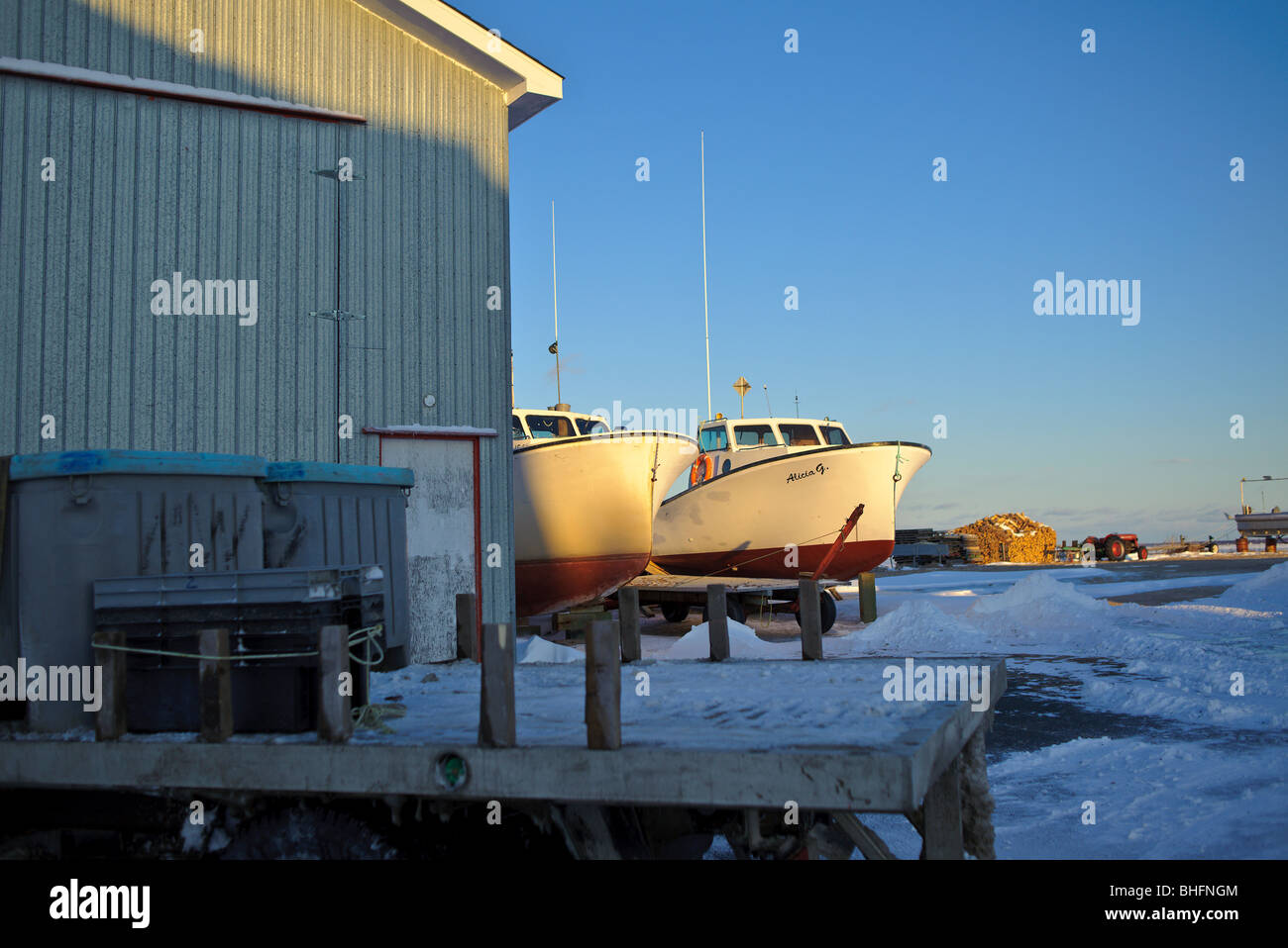 Lobster boats out of the water during winter along the frozen shores of ...