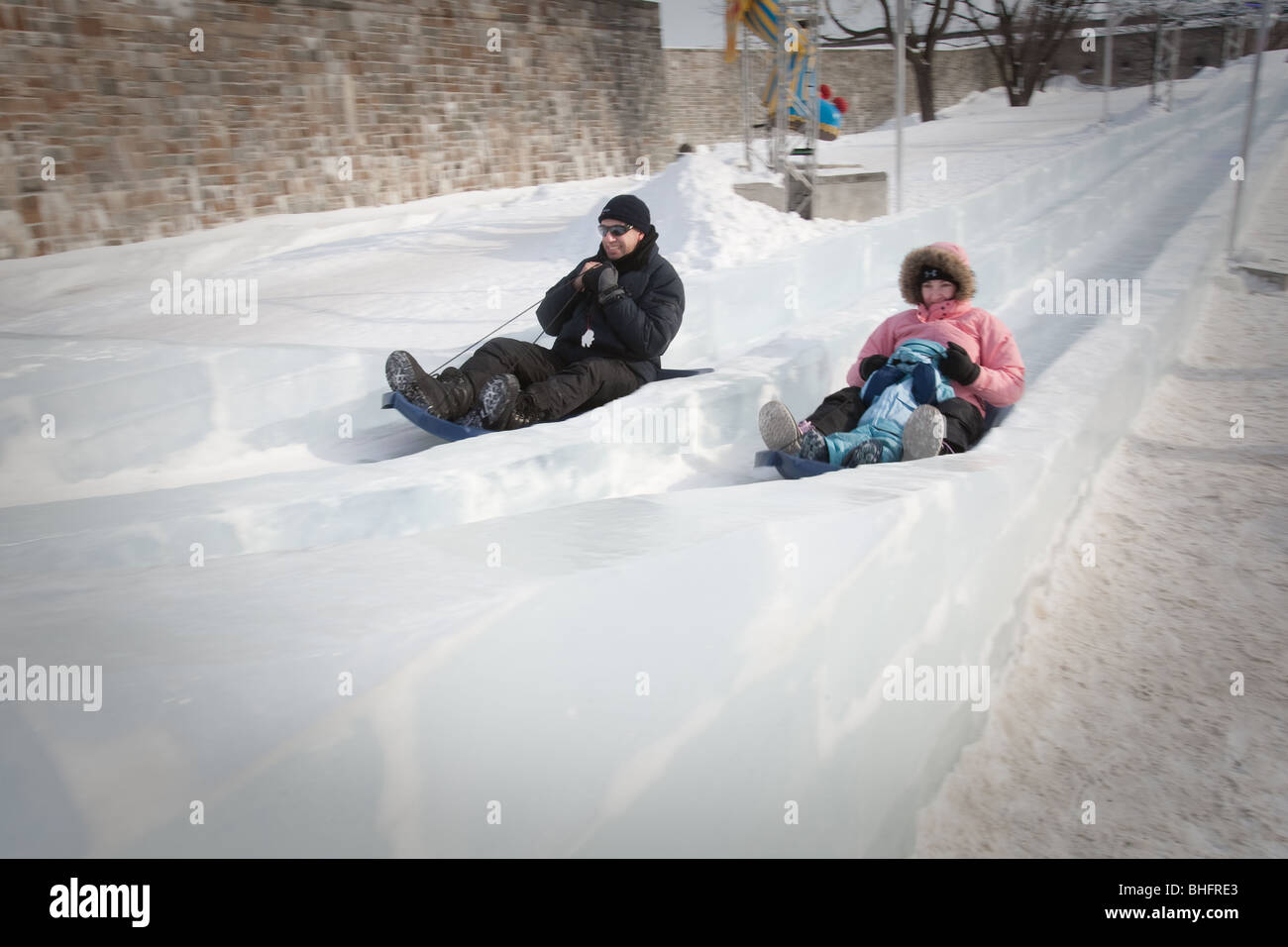 A man rides an ice slide with his wife and his daughter at the Quebec ...