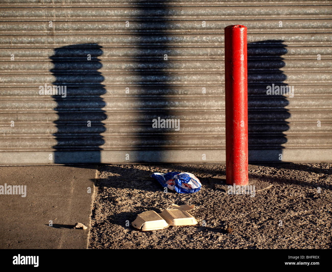 sunlit red post with enlarged shadows from low sun shining on steel ...