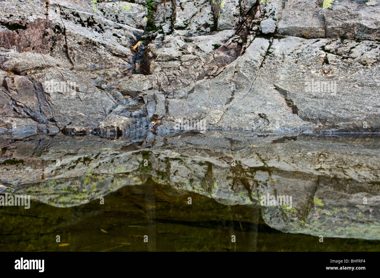 Water-polished rocks in channel of the Sand River reflected in pool of ...