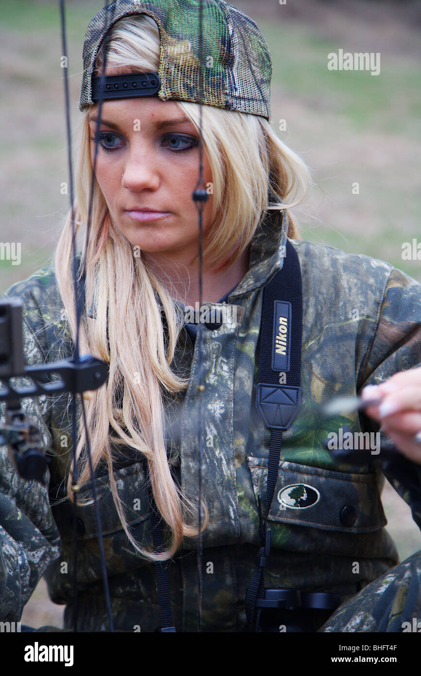 YOUNG WOMAN 21 Y.O. FEMALE HUNTER SITTING ON LOG PREPARING 80 POUND BOW ...