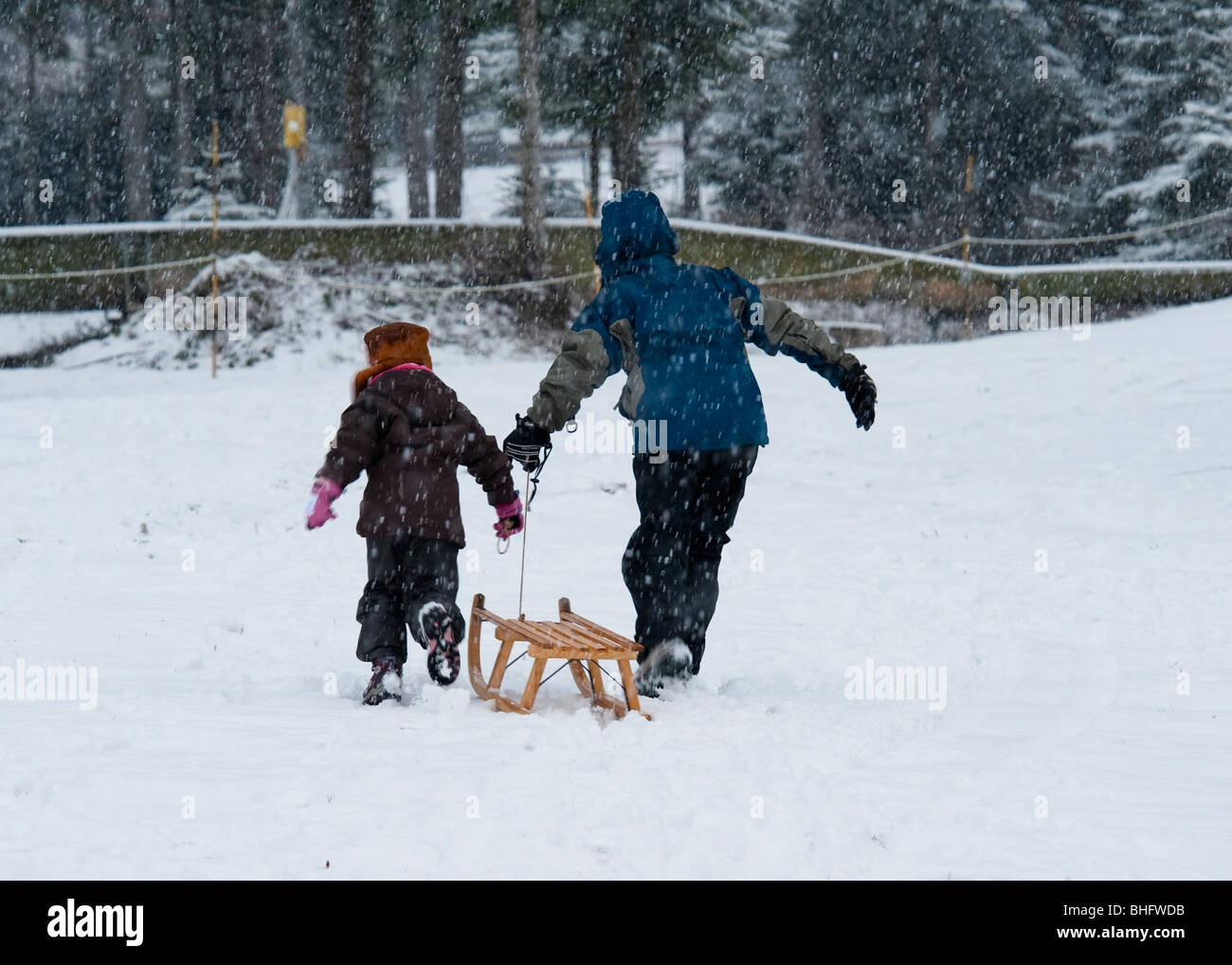 Mother and daughter pull traditional wooden sled back up snow covered ...