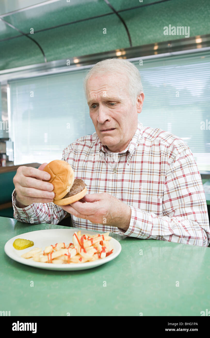 Worried old man looking at a burger Stock Photo - Alamy