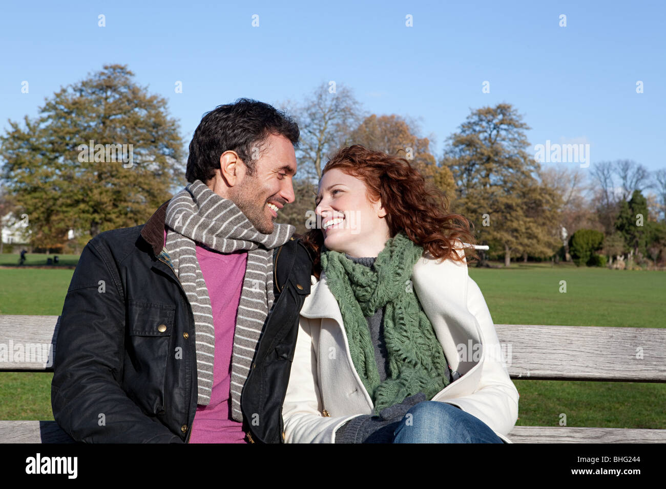A couple sitting face to face on a park bench Stock Photo - Alamy